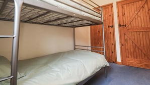 Quarto com beliche, porta de madeira e escada de metal.