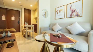 Quarto de hotel moderno com sofá, mesa redonda, pequeno vaso decorativo e uma pintura de um mapa-múndi na parede.