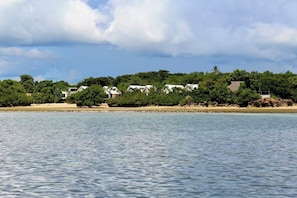 Uma área costeira com edifícios brancos, uma praia de areia e vegetação densa.
