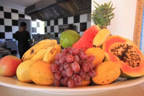 Uma tábua de frutas variadas, incluindo mangas, mamão e uvas.
