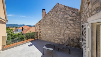 Uma varanda com parede de pedra, uma mesa e uma cadeira.