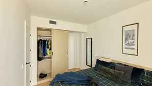 Um quarto com uma cama, guarda-roupa, espelho e um quadro na parede.