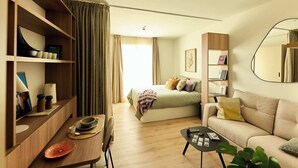 Uma sala moderna com sofá, mesa de centro, área de jantar com mesa e cadeiras, e quarto com cama e cortinas.