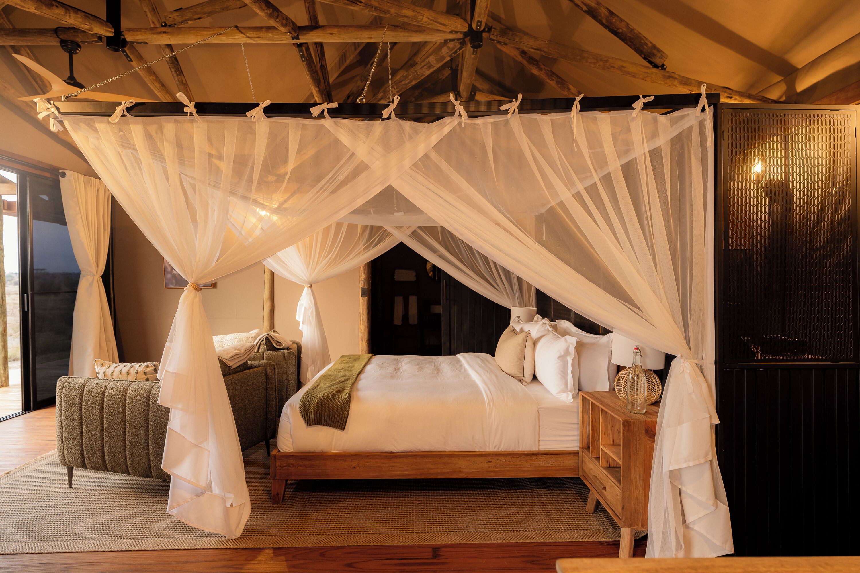 Quarto com cama de dossel, cabeceira de madeira e mesa de cabeceira com abajur.