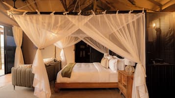Quarto com cama de dossel, cabeceira de madeira e mesa de cabeceira com abajur.