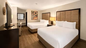Quarto de hotel com duas camas, uma escrivaninha, uma televisão e um quadro na parede.