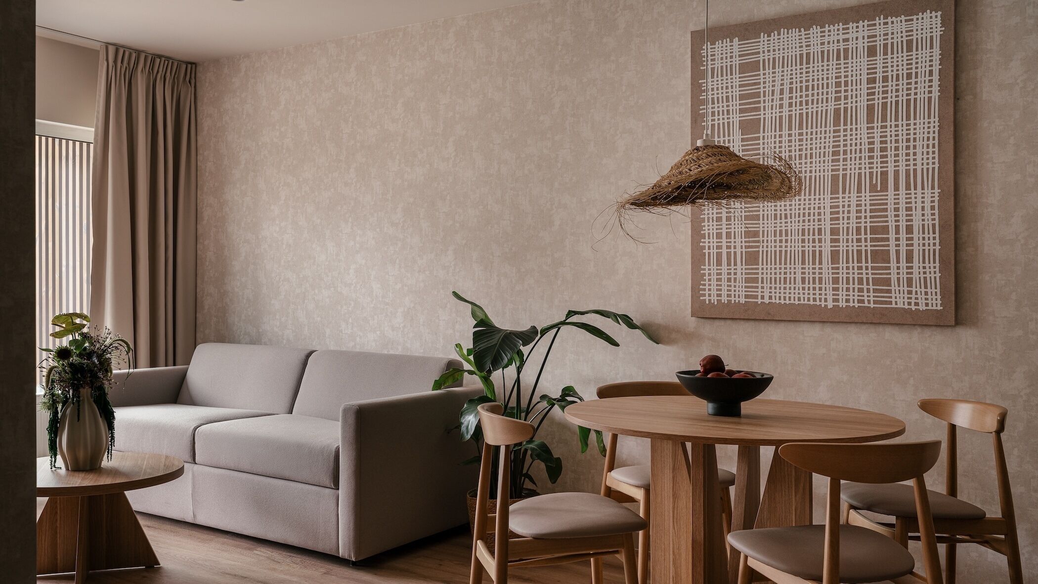 Uma sala de estar moderna com sofá, mesa de jantar, cadeiras, luminária pendente e uma obra de arte na parede.