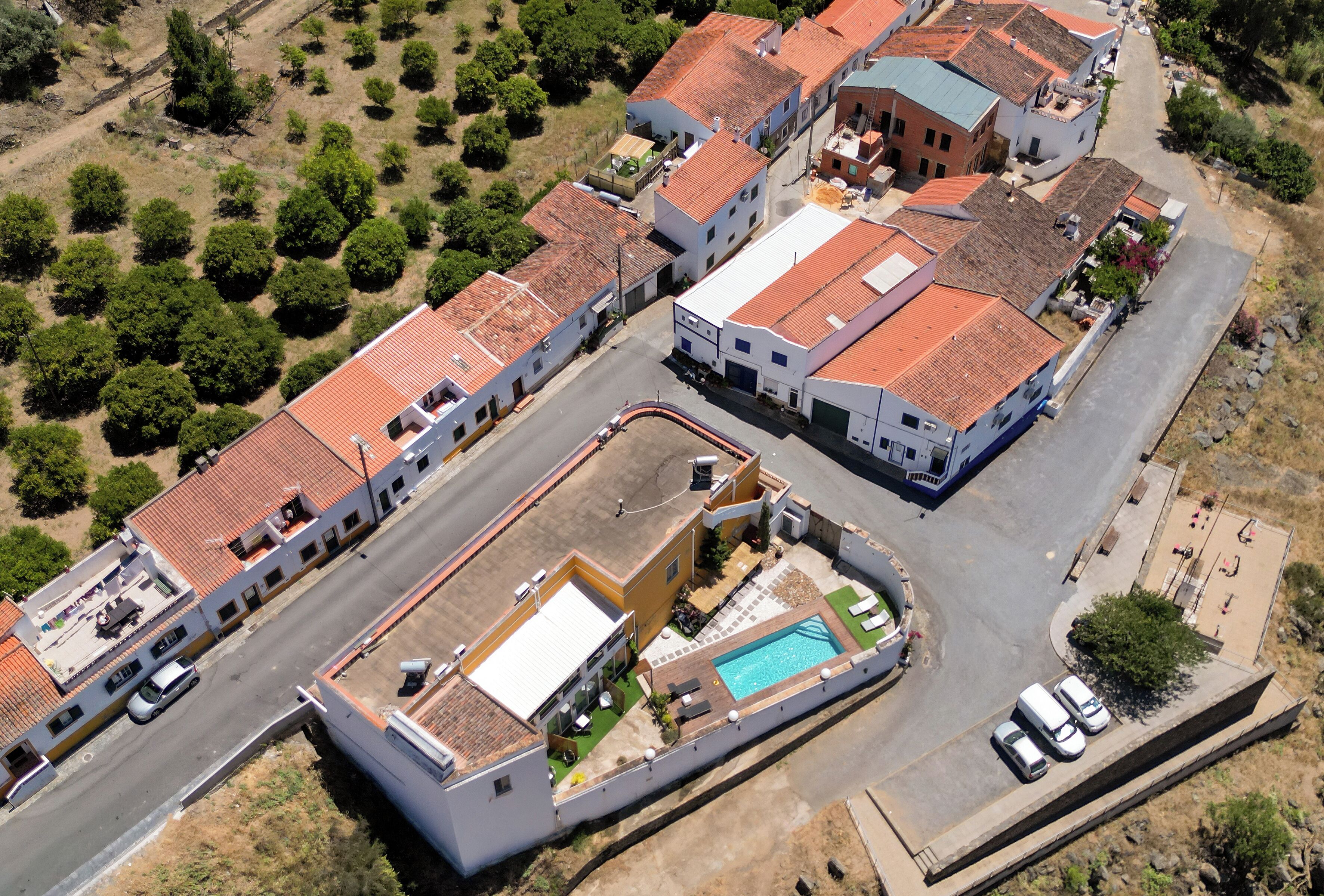 Vista aérea de uma área residencial com vários edifícios, piscina e estrada.