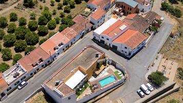 Vista aérea de uma área residencial com vários edifícios, piscina e estrada.