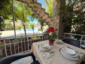 Mesa posta para refeição, com vista para a piscina e jardim.
