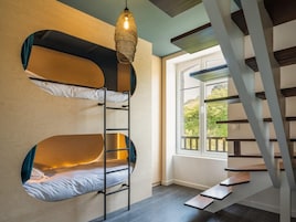 Uma cama beliche com escada, um lustre pendurado e uma escadaria.