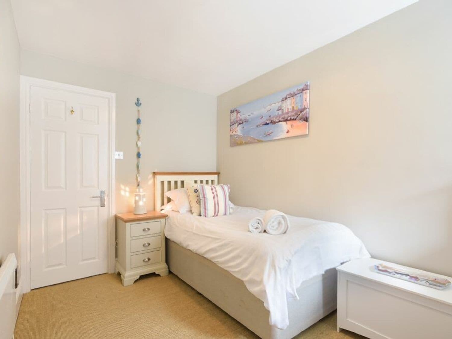 Quarto com uma cama, mesa de cabeceira e um quadro na parede.