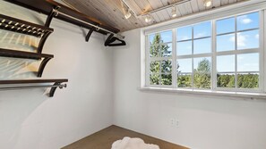 Um quarto com uma janela grande, teto de madeira e um cabideiro suspenso.