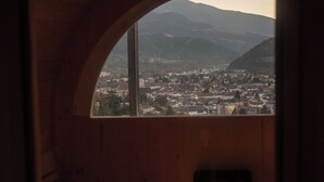 Quarto com uma grande janela em arco, um banco de madeira e uma cama.