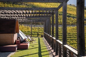 Uma área de estar coberta ao ar livre com vista para um jardim paisagístico.