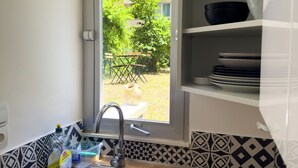 Cozinha com pia, janela e vista para uma varanda com mobiliário de exterior.