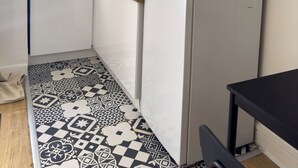 Uma cozinha compacta com geladeira, pia e ladrilhos estampados.