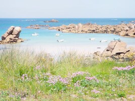 Paisagem costeira com águas claras, barcos e formações rochosas.