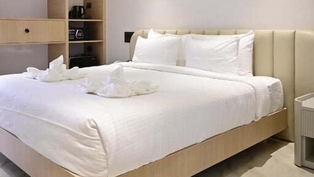 Quarto de hotel moderno com uma cama grande, ventoinha no teto, estantes embutidas e piso de mármore.