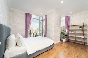 Quarto moderno com cama, piso de madeira, parede de tijolos e vista para a cidade.