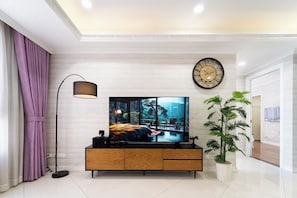 Uma sala de estar moderna com uma televisão de tela plana grande, armário de madeira, abajur e um vaso de planta.