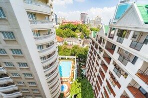 Um hotel moderno com vários sacadões, piscina no terraço e vista para edifícios e áreas verdes ao redor.