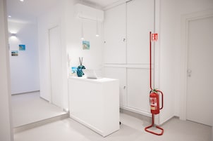 Um saguão de hotel moderno, com um balcão de recepção, um extintor de incêndio e uma porta.