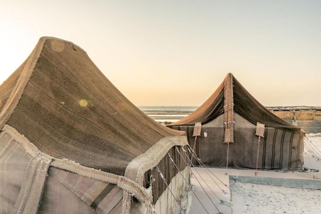 Uma estrutura em forma de tenda com telhado pontiagudo, possivelmente um alojamento temporário ou espaço para eventos.