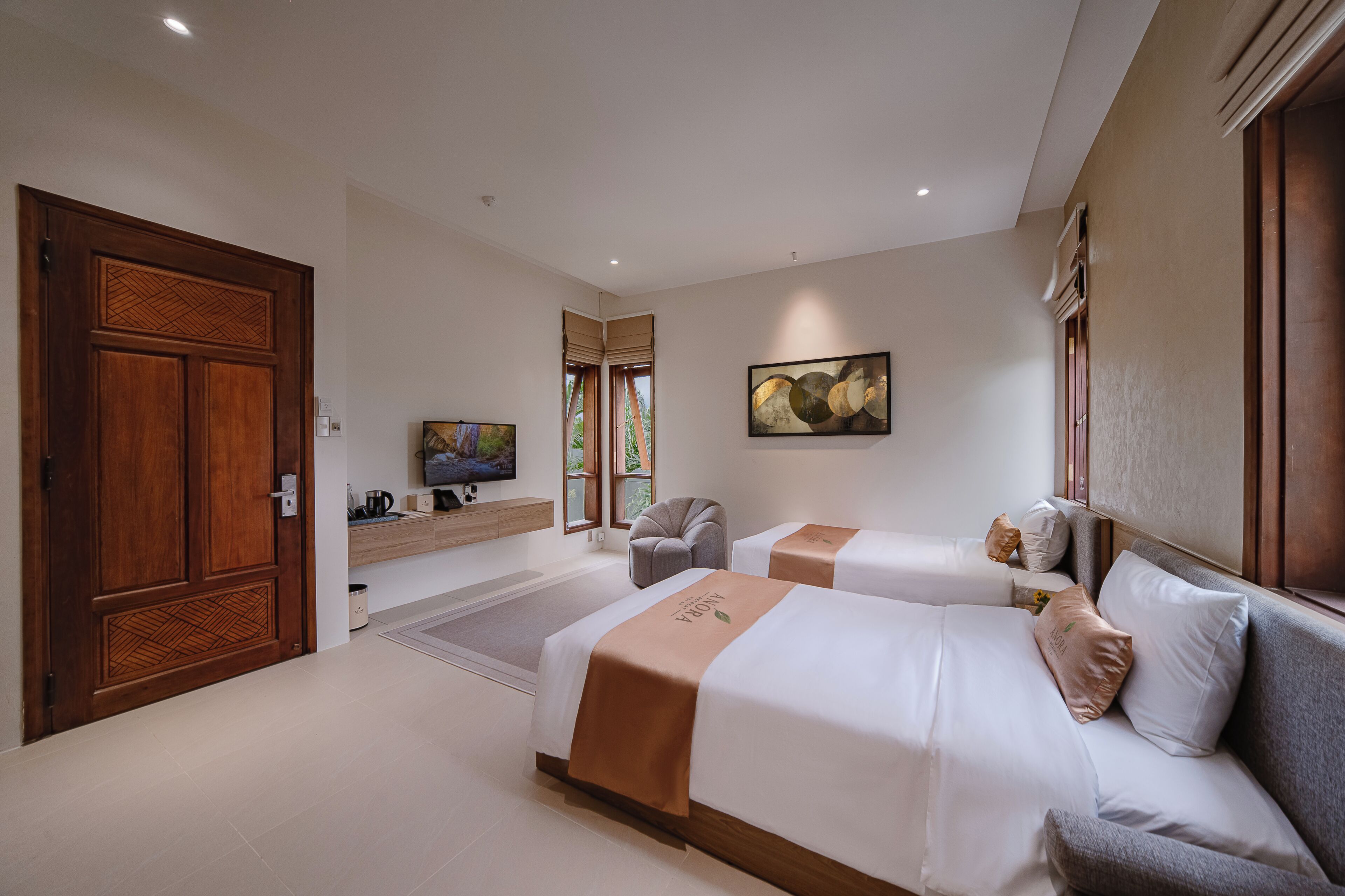 Quarto de hotel com duas camas, um sofá, uma televisão e um quadro na parede.