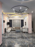 Uma sala de estar moderna com piso de mármore, um sofá, uma mesa de centro e cadeiras transparentes.