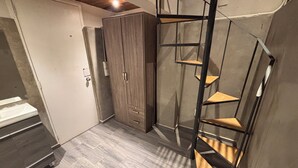 Quarto compacto com guarda-roupa, escada e uma cama.