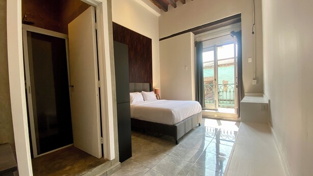Quarto de hotel com cama, banheiro e varanda.