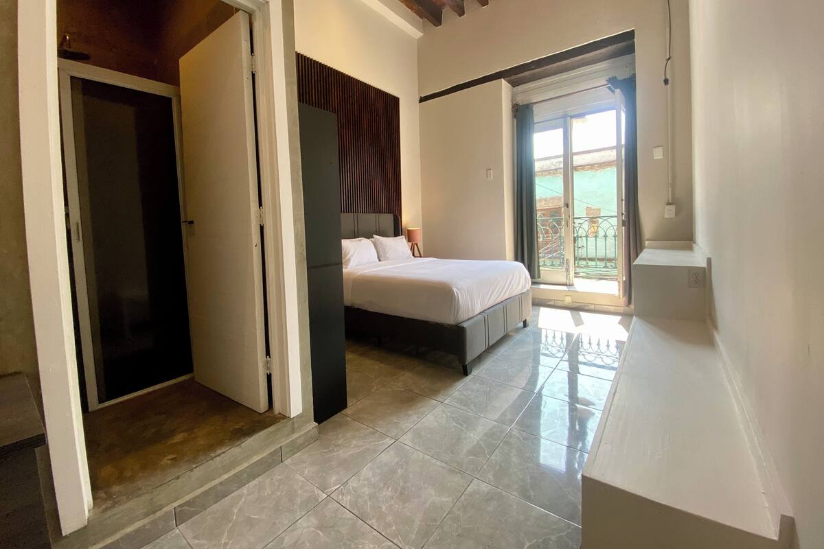 Quarto de hotel com cama, banheiro e varanda.