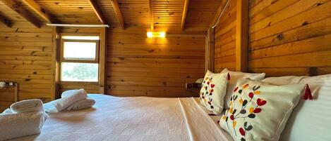 Quarto de cabana de madeira com cama, almofadas, janela e ar condicionado.