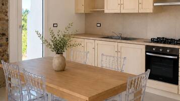 Cozinha moderna com mesa e cadeiras de madeira, fogão e armários.