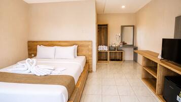 Quarto de hotel com cama, televisão, secretária com espelho e zona de duche.