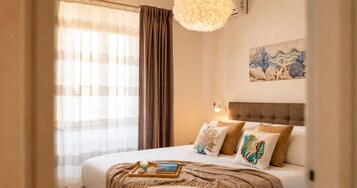 Quarto de hotel com cama, mesa de cabeceira, luminária na parede e um quadro.