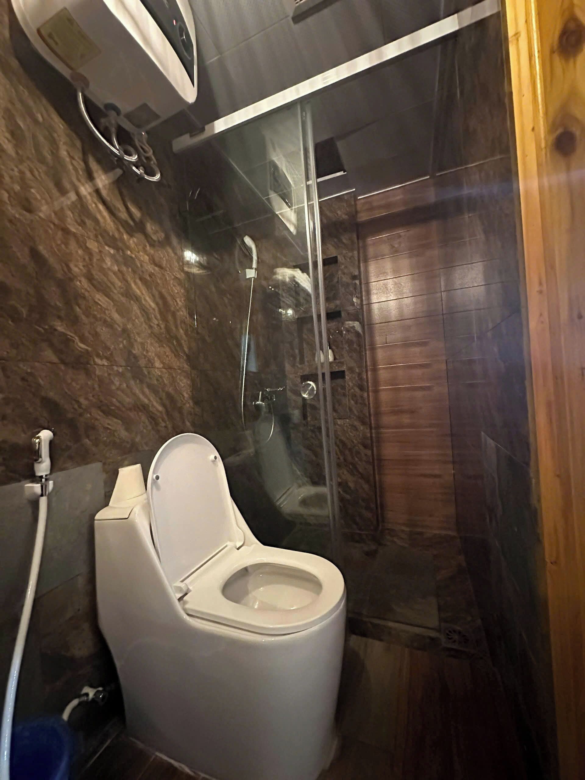 Casa de banho com sanita, cabine de duche e parede de mármore.