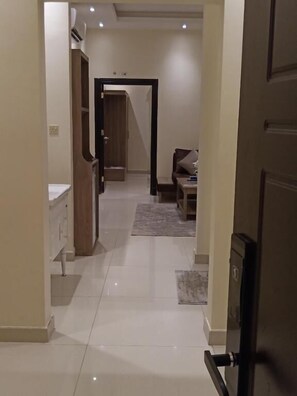 Um corredor com uma porta, uma pequena mesa com uma cadeira e um tapete no chão.