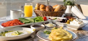 Uma mesa de café da manhã com diversos alimentos, uma xícara de café e um copo de suco de laranja.