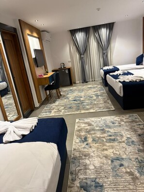 Quarto de hotel com duas camas, uma escrivaninha, uma cadeira, um espelho e uma televisão.