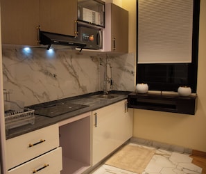 Uma cozinha com bancada de mármore, forno embutido, pia e janela com persianas.