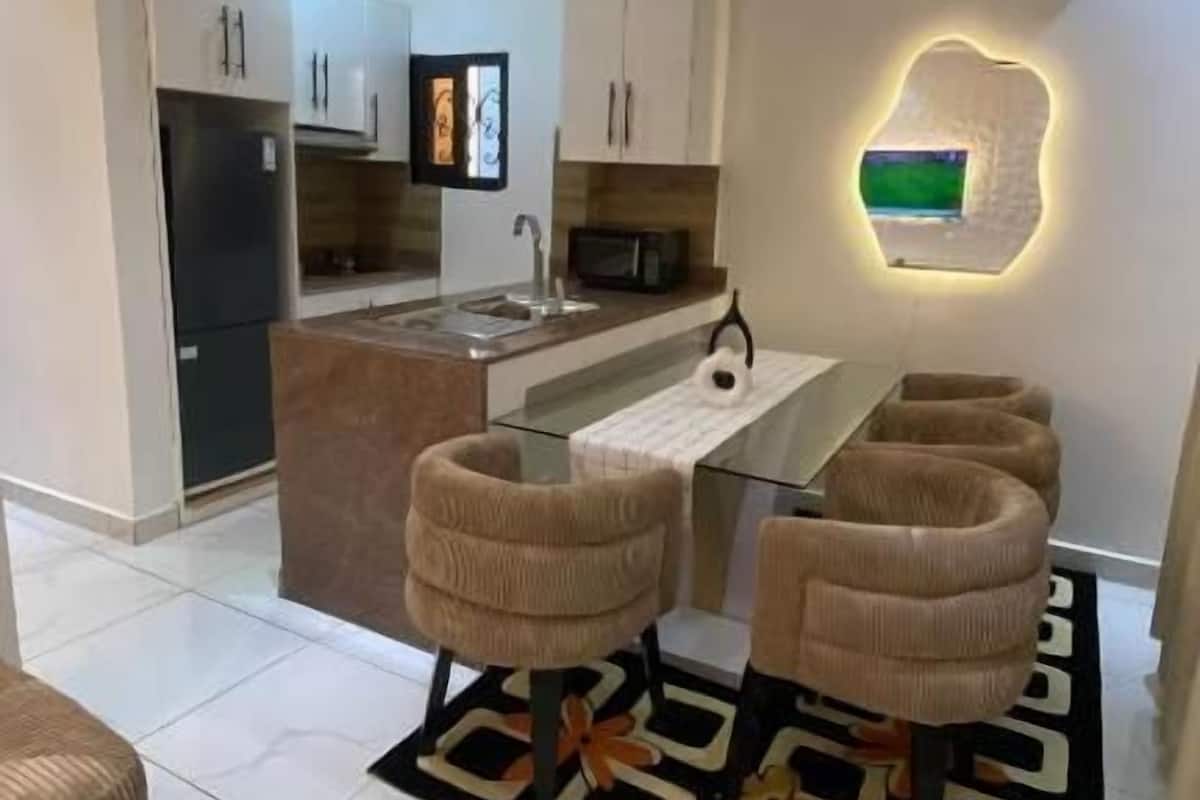 Cozinha moderna com armários brancos, uma ilha central e um espaço de refeições com duas cadeiras.