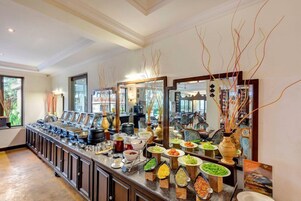 Buffet com diversos pontos de comida, um balcão comprido e um espelho refletindo o espaço.