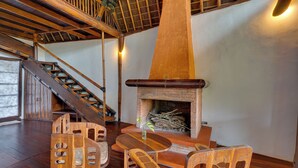 Interior em madeira com lareira, escada e área de jantar com mobiliário de madeira.