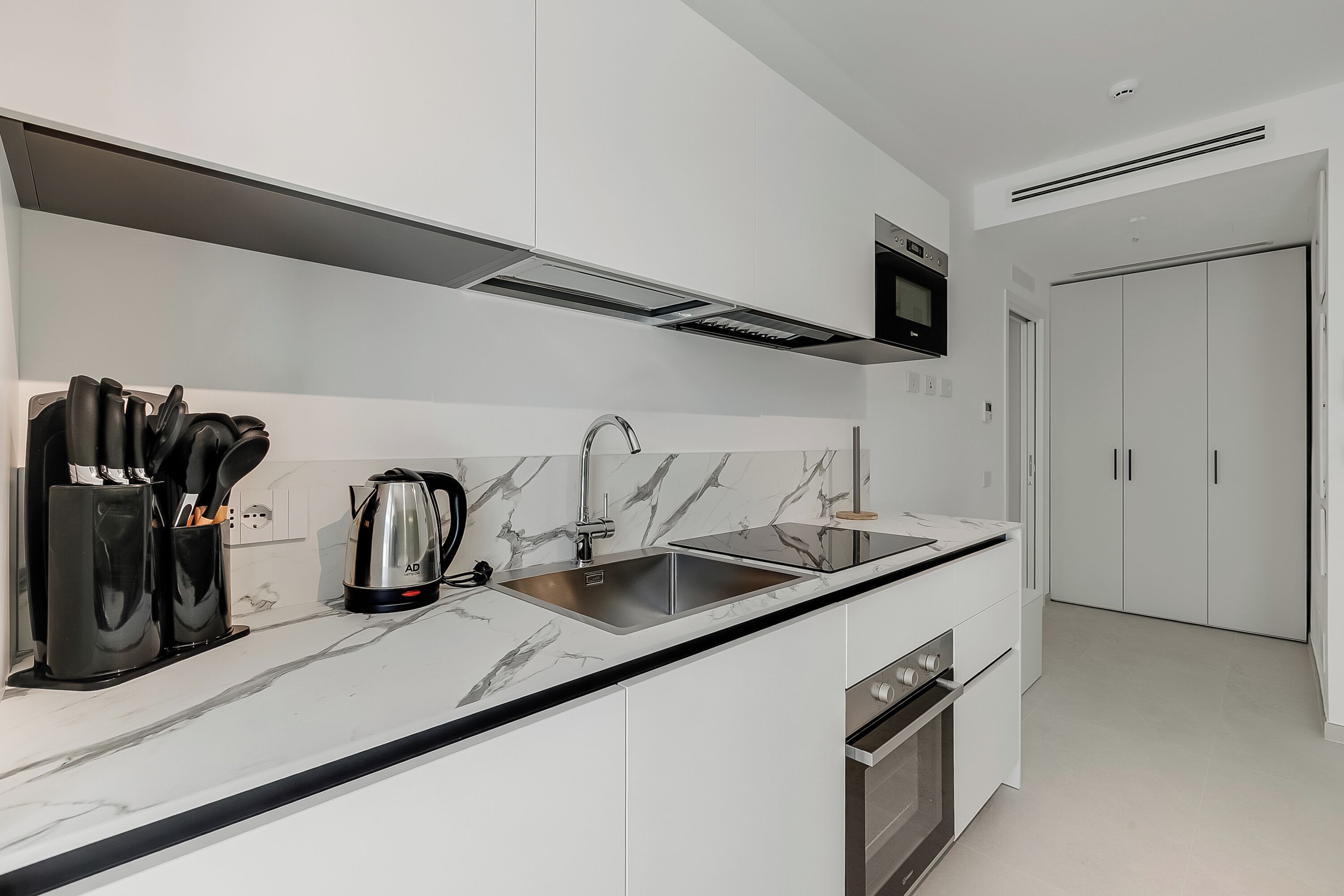 Uma cozinha moderna com bancada de mármore, eletrodomésticos de aço inoxidável e forno embutido.