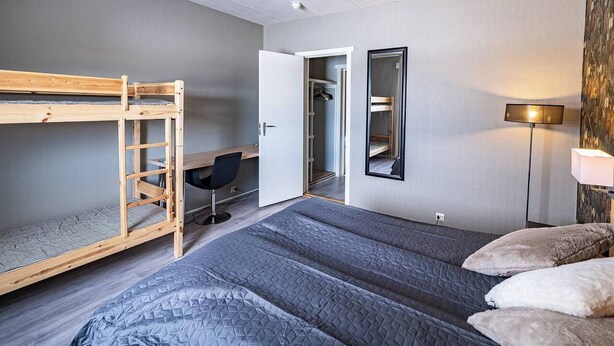 Quarto com beliches, uma escrivaninha, uma cadeira, guarda-roupa e abajur.