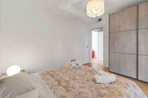 Quarto moderno com cama, abajur, luminária na parede e guarda-roupa.