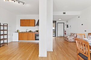 Cozinha moderna com armários de madeira, geladeira branca e área de jantar com mesa e cadeiras de madeira.