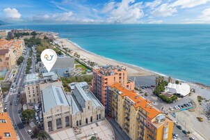 Uma área costeira urbana com edifícios, uma praia e céu claro.